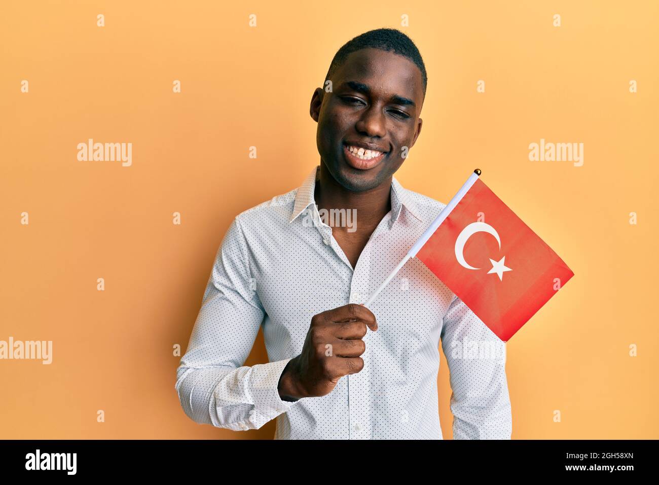 Young african american man holding turkey flag looking positive and ...