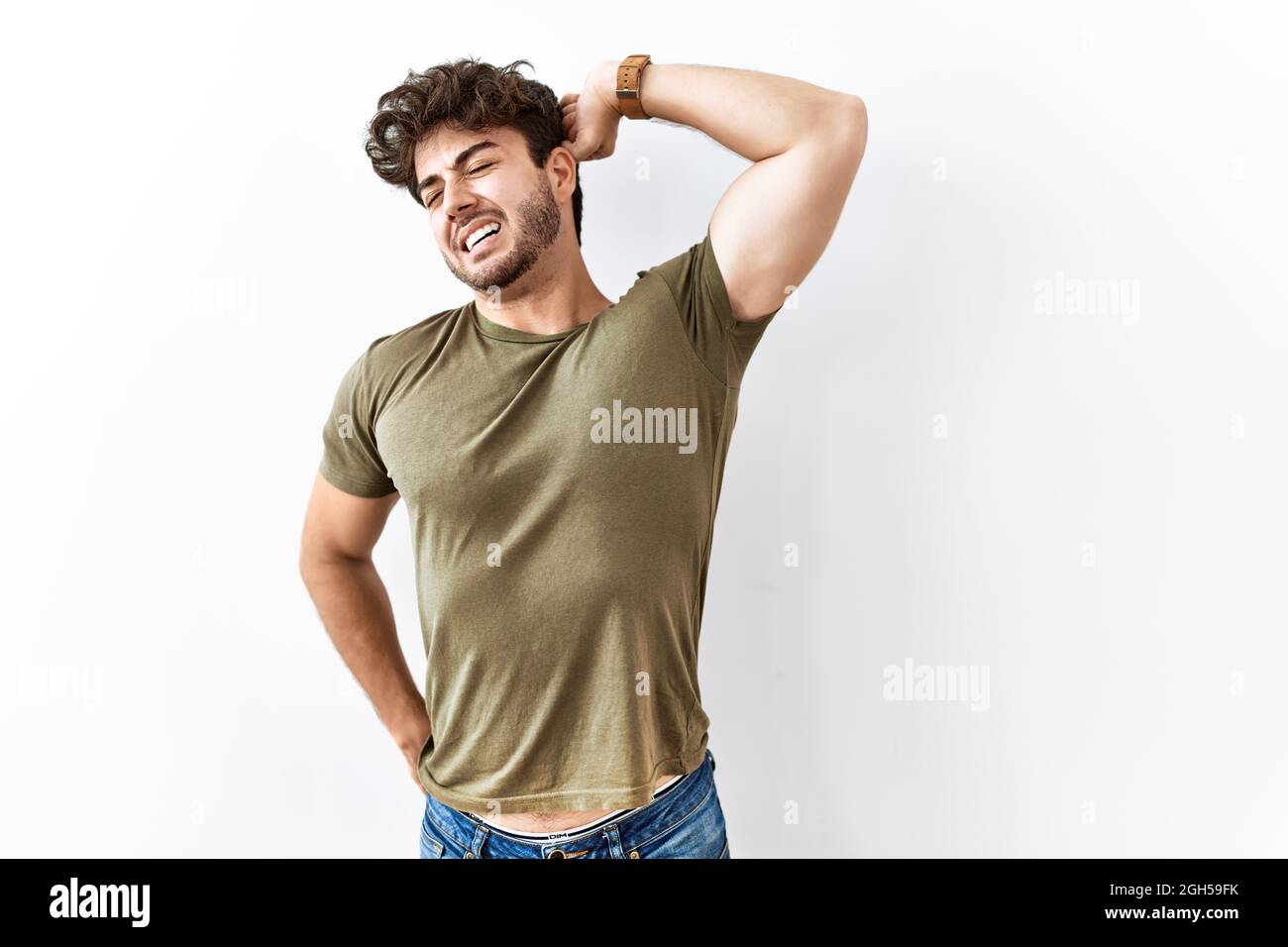 Hispanic man standing over isolated white background stretching back ...