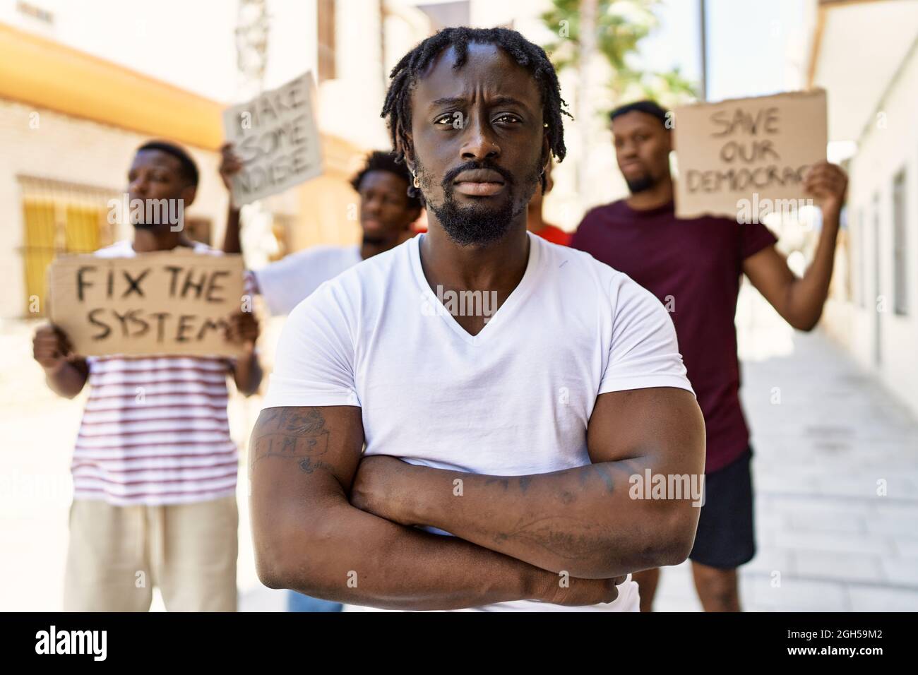 Young activist man with arms crossed gesture standing with a group of ...