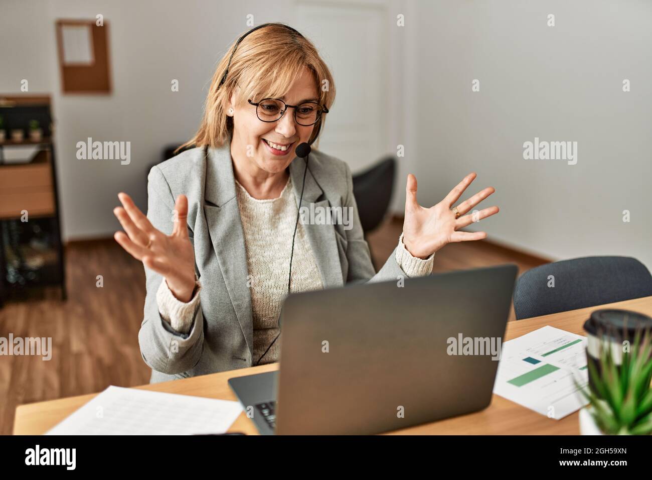 Middle age call center agent having video call using laptop at the ...