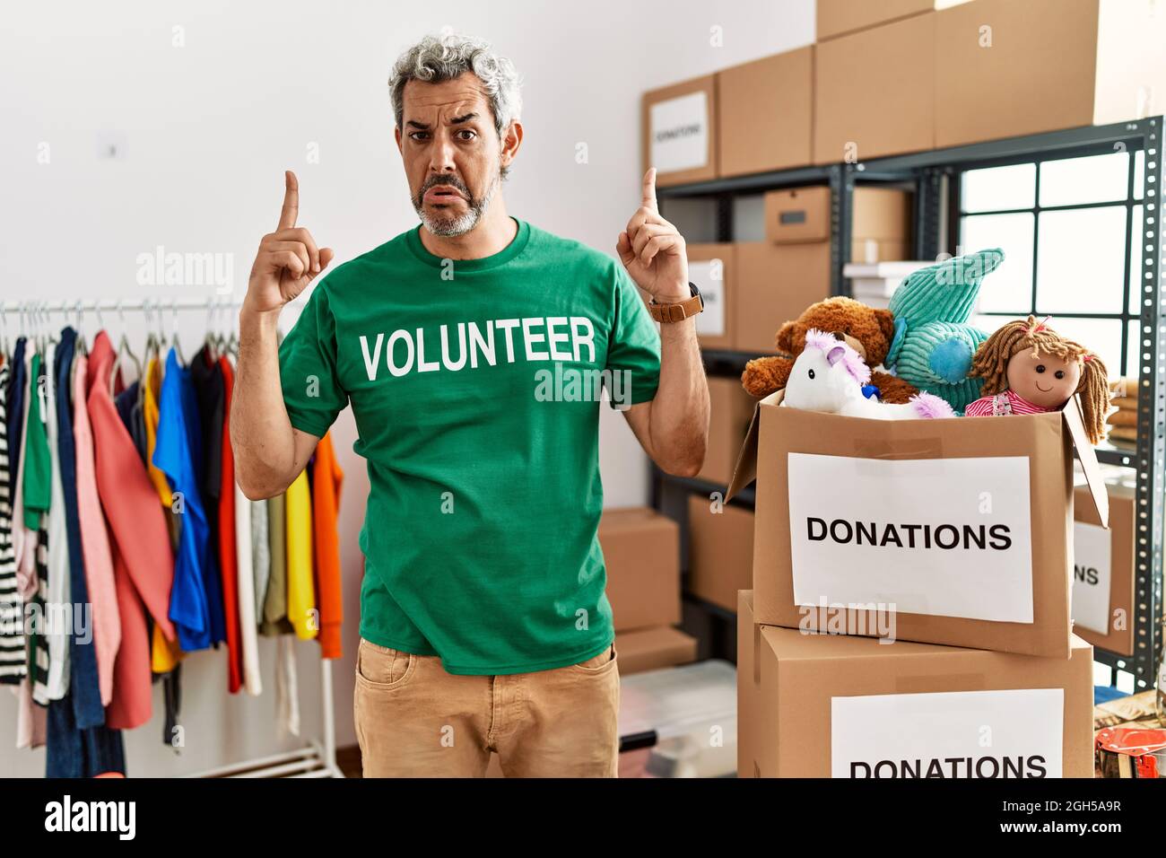 Middle age hispanic man wearing volunteer t shirt at donations stand ...