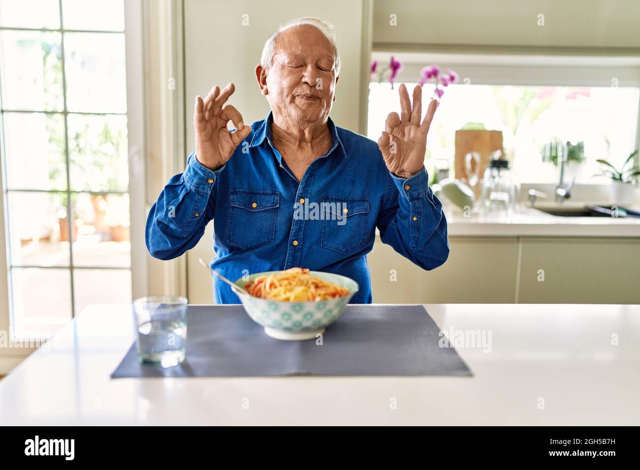 Senior man with grey hair eating pasta spaghetti at home relax and ...