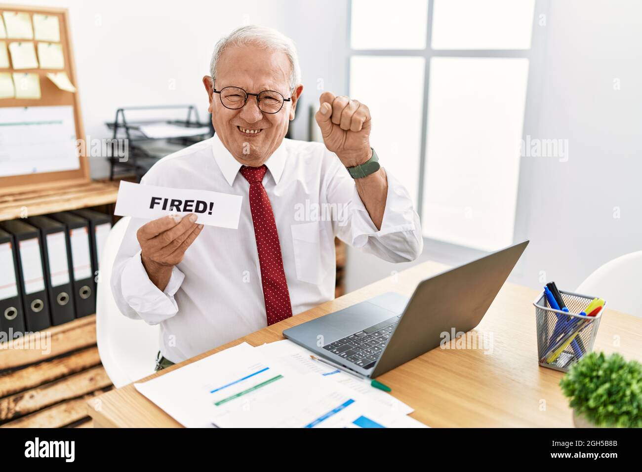 Senior business man holding fired banner at the office annoyed and ...