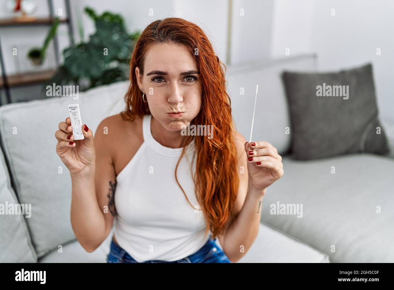 Young redhead woman doing coronavirus infection nasal test puffing ...