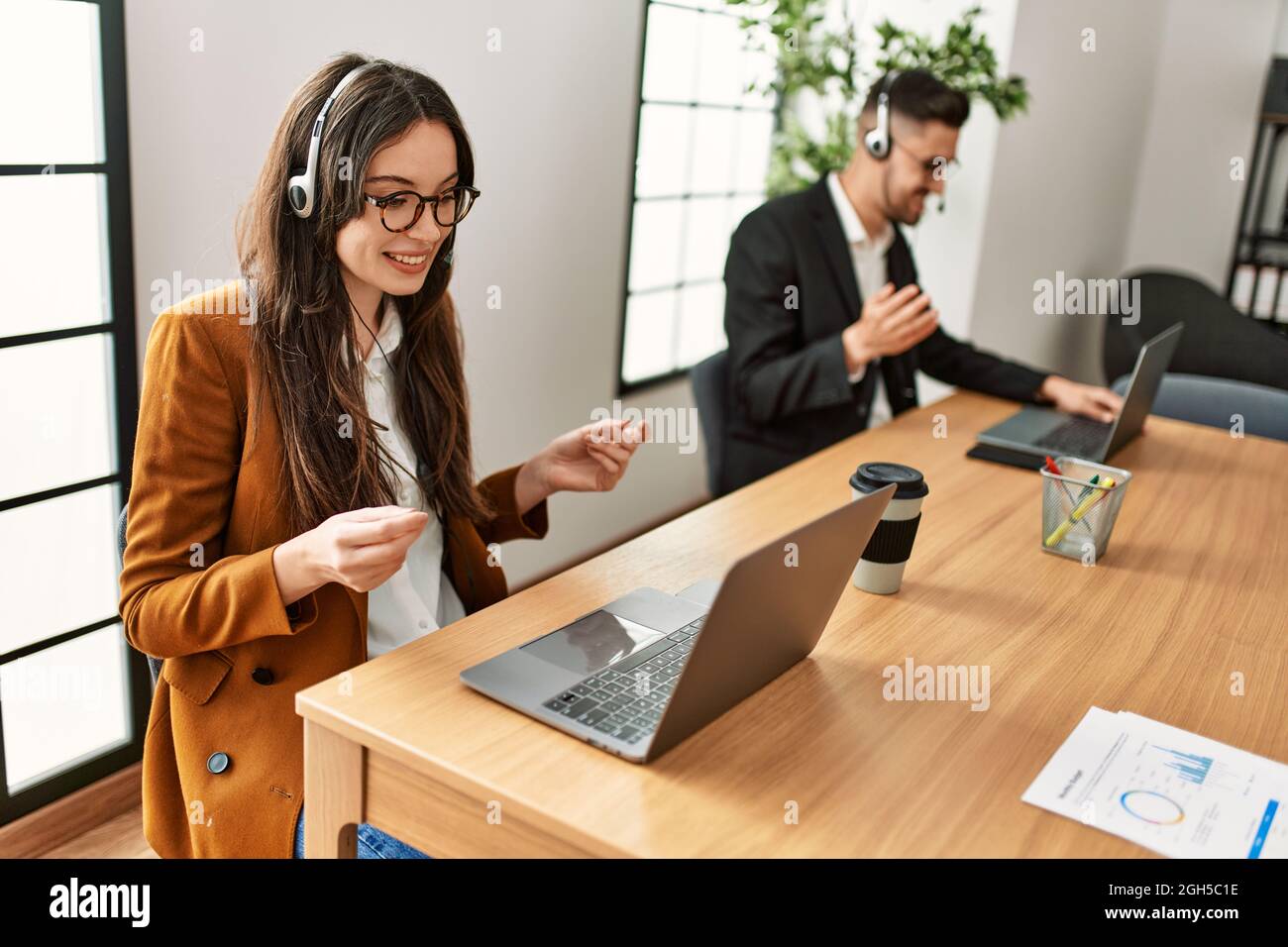 Two hispanic call center agents working at the office Stock Photo - Alamy