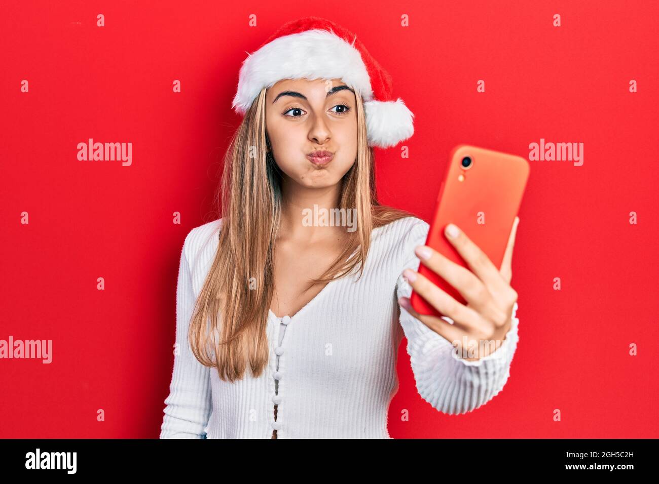 Beautiful Hispanic Woman Wearing Christmas Hat Using Smartphone Puffing