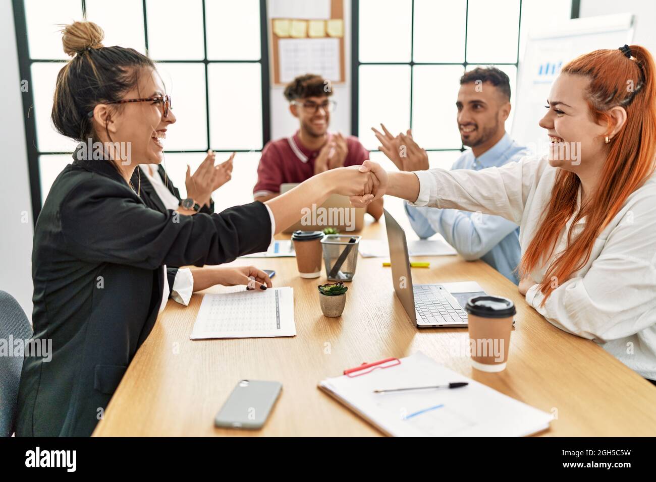 Group of business workers smiling and clapping to partners handshake at ...