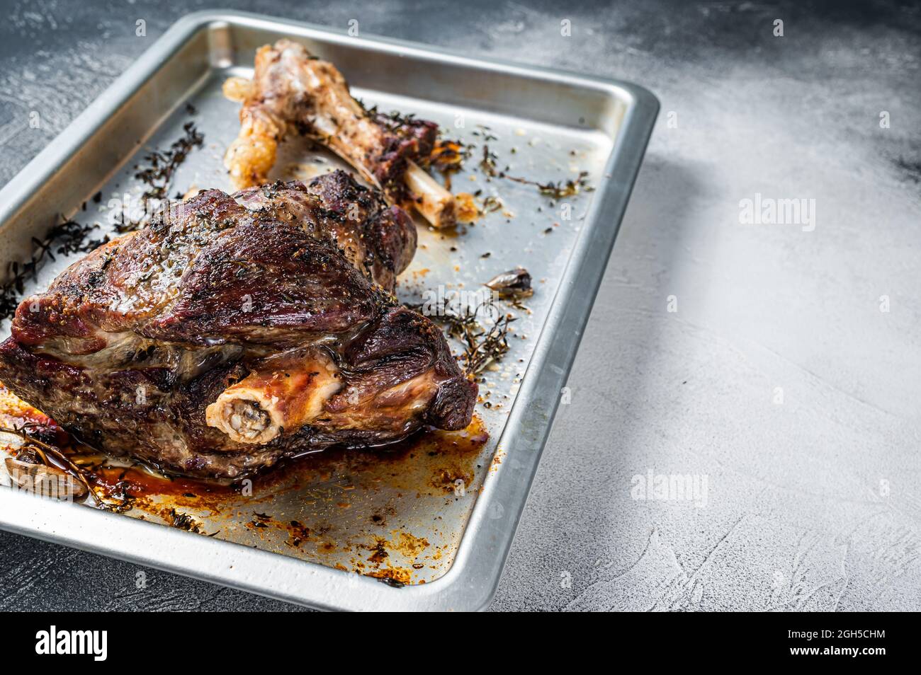 Roasted lamb mutton whole leg in a baking dish. White background. Top ...