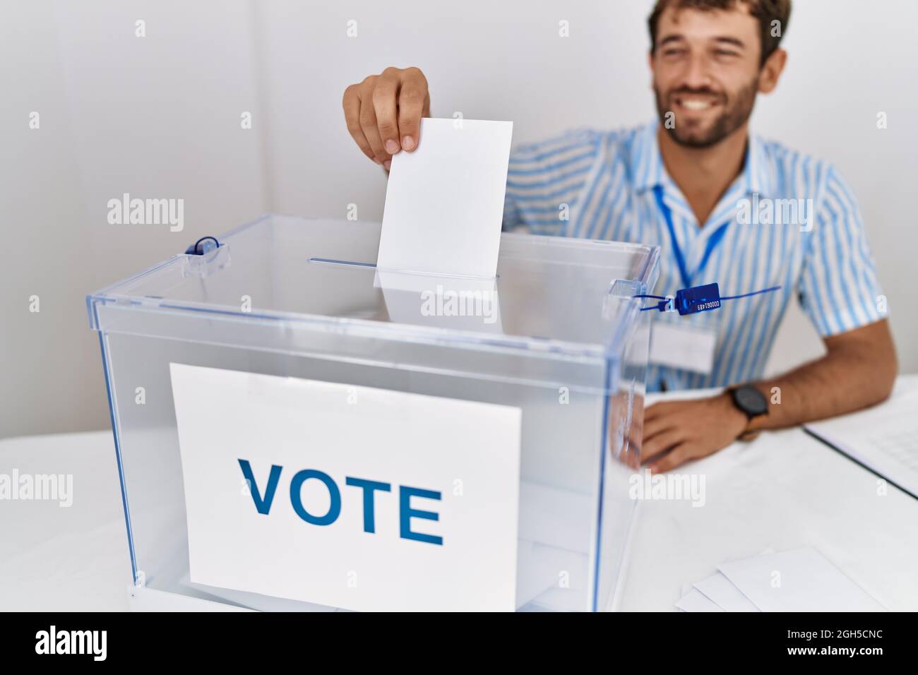 Young hispanic politic party worker smiling happy putting vote in ...