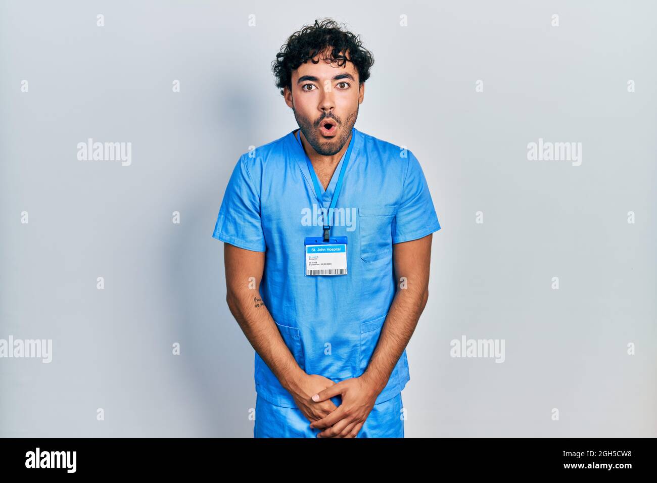 Young hispanic man wearing blue male nurse uniform afraid and shocked ...