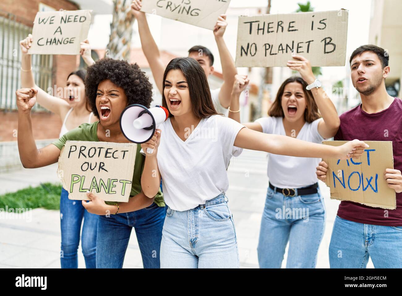 Group of young activists people protesting holding banner and using ...