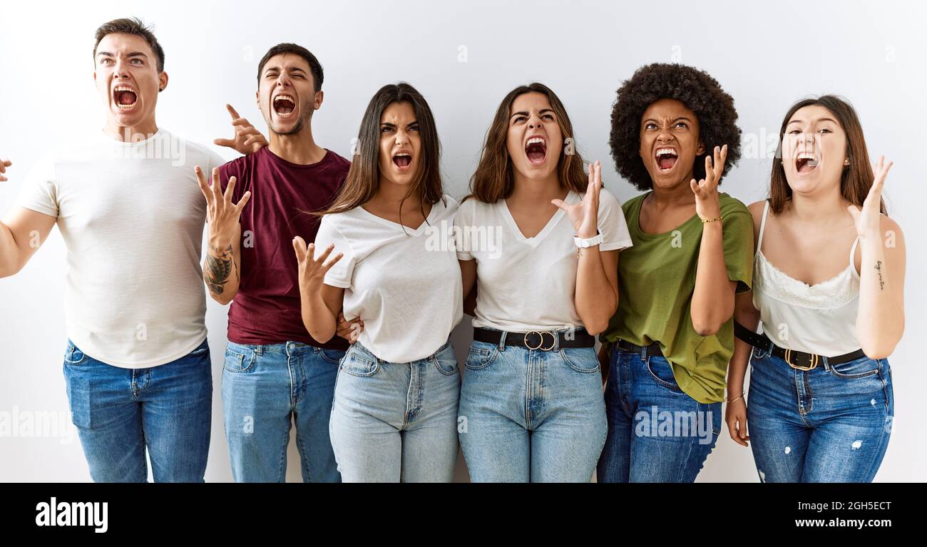 Group of young friends standing together over isolated background crazy ...