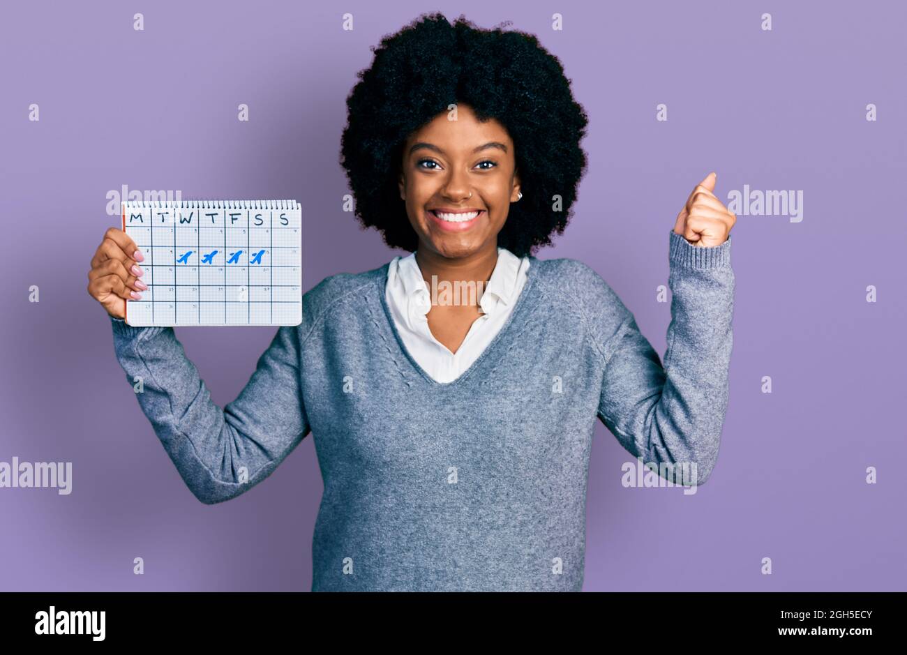 Young african american woman holding travel calendar screaming proud ...