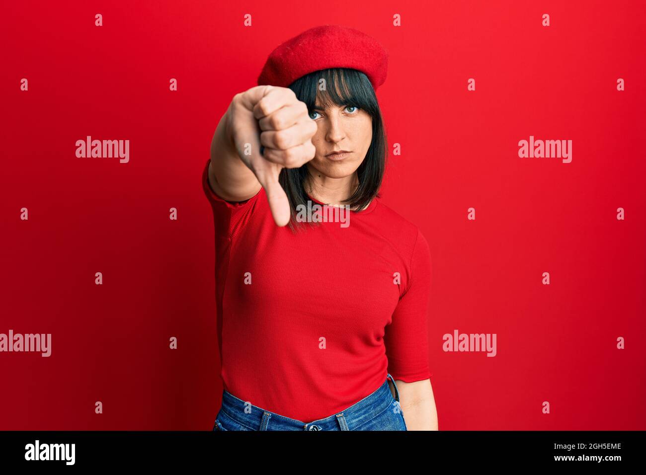 Young hispanic woman wearing french look with beret looking unhappy and ...