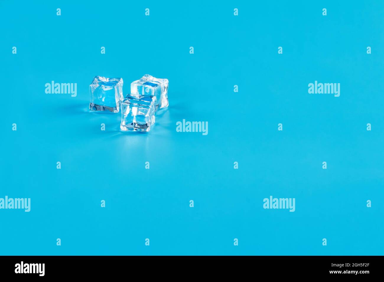 Three ice cubes on a blue background Stock Photo - Alamy