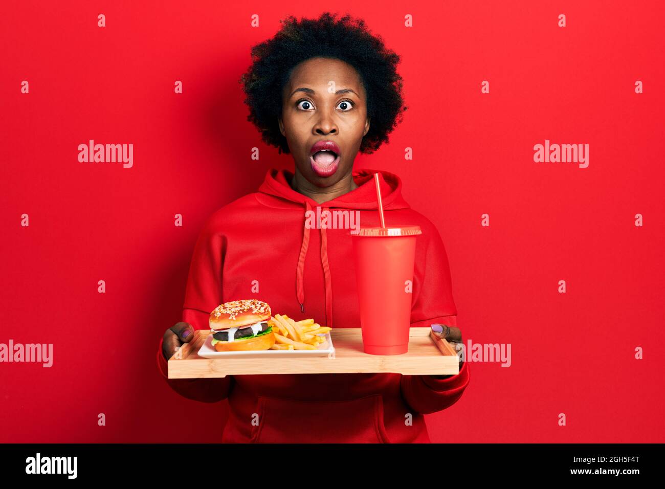 Young african american woman eating a tasty classic burger with fries ...