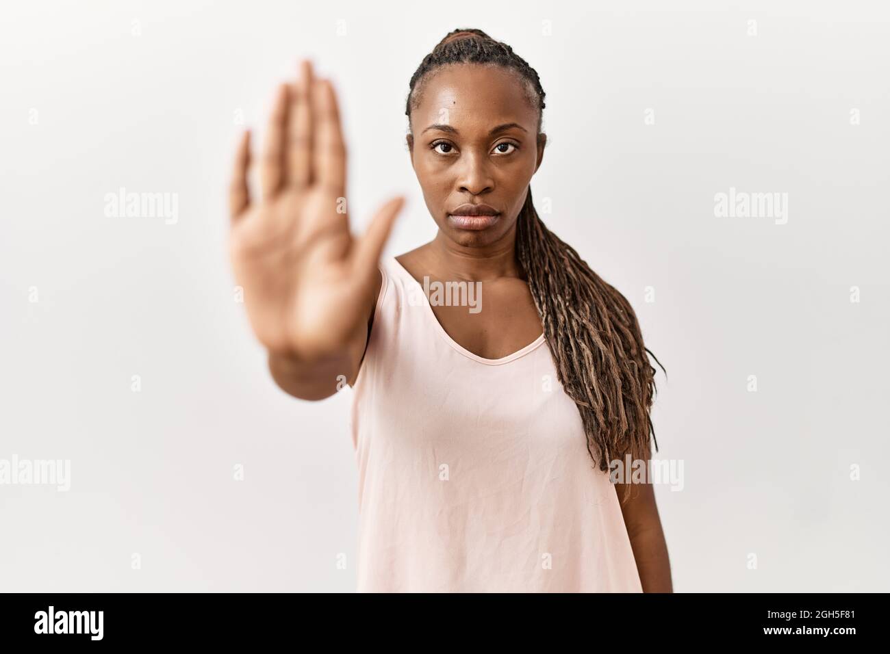 Black woman with braids standing over isolated background doing stop ...