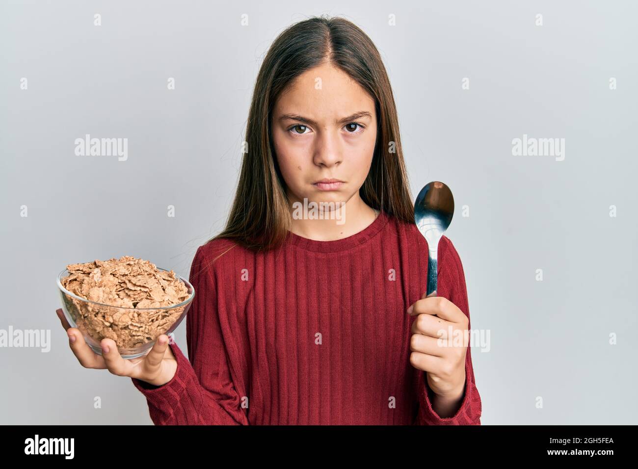 Beautiful brunette little girl eating healthy whole grain cereals ...