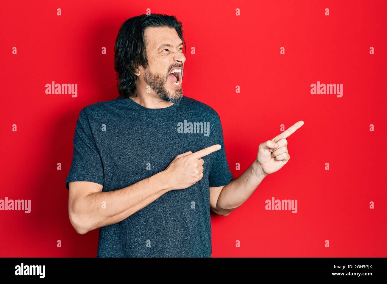Middle age caucasian man pointing with fingers to the side angry and ...