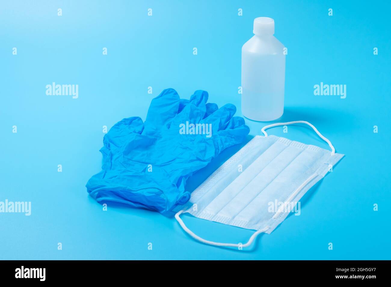 Disposable medical mask, antiseptic and latex glove on light blue ...