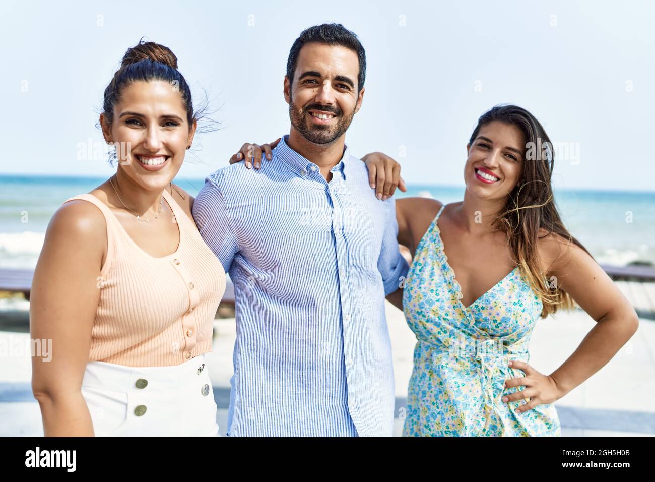 Three young hispanic friends smiling happy and hugging at the beach ...