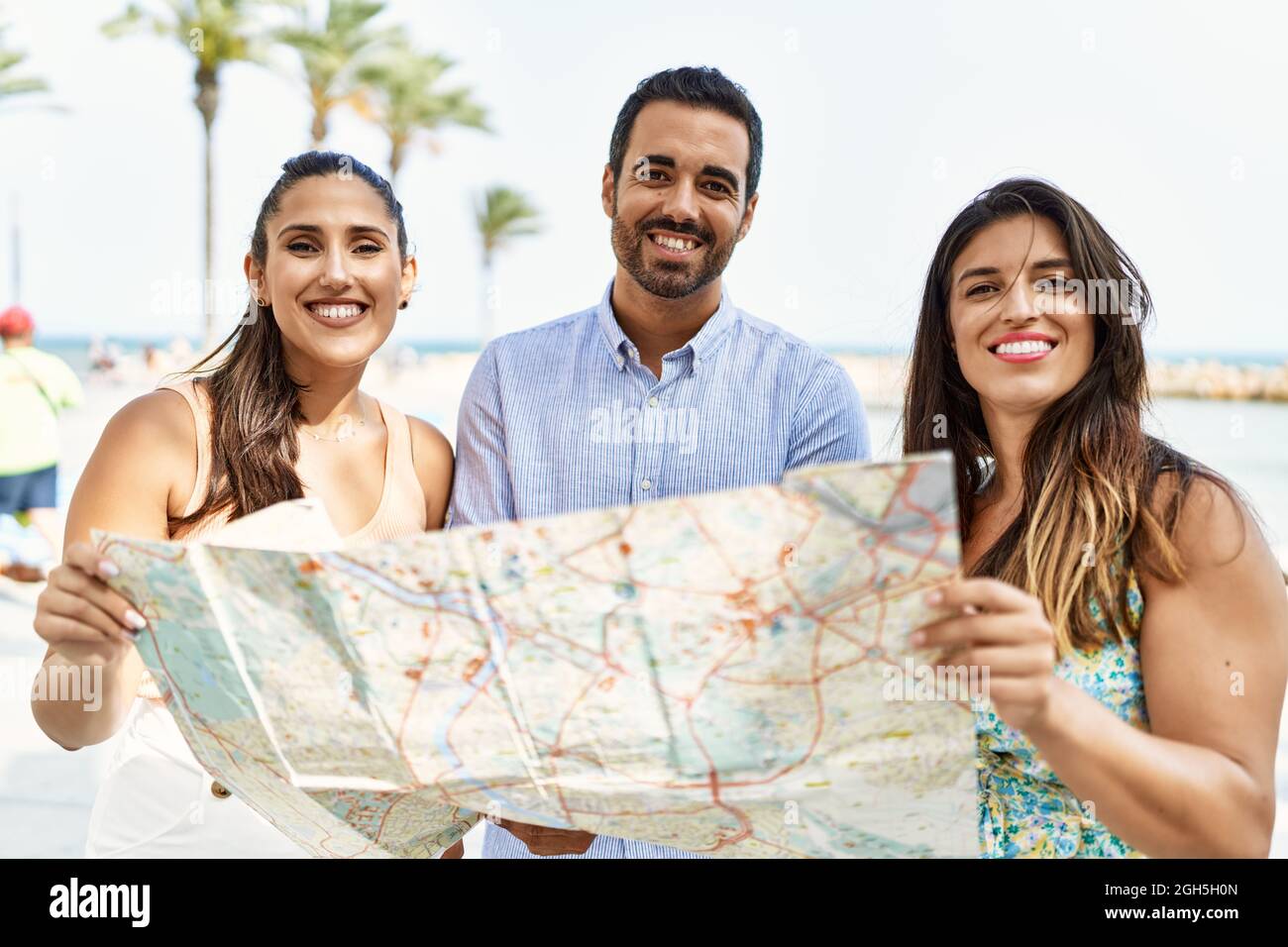 Three young hispanic friends smiling happy searching route on city map ...