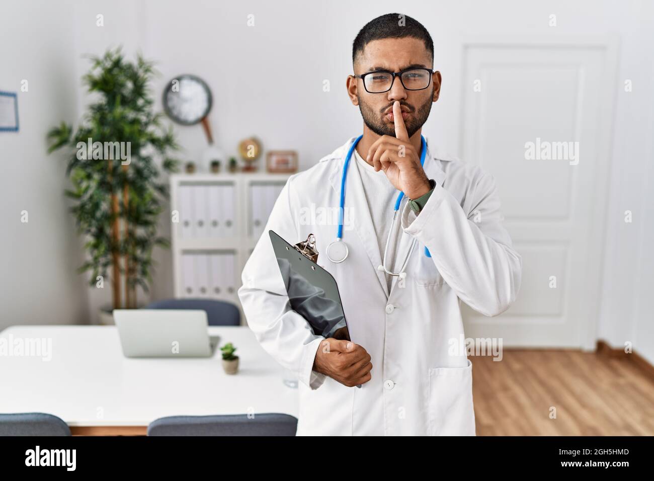 Young indian man wearing doctor uniform and stethoscope asking to be ...