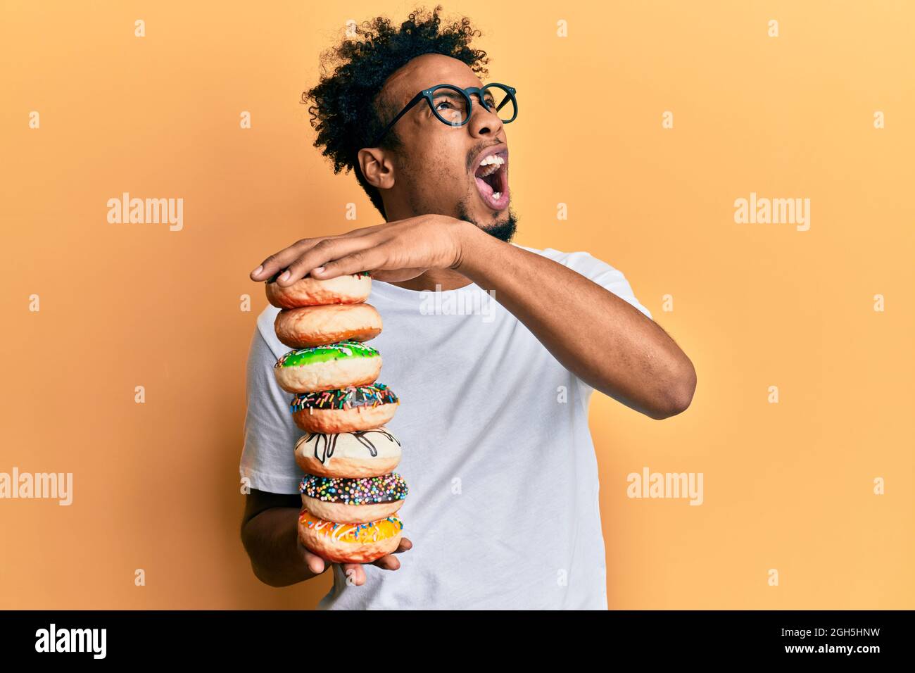 Young african american man with beard holding pile of tasty colorful ...
