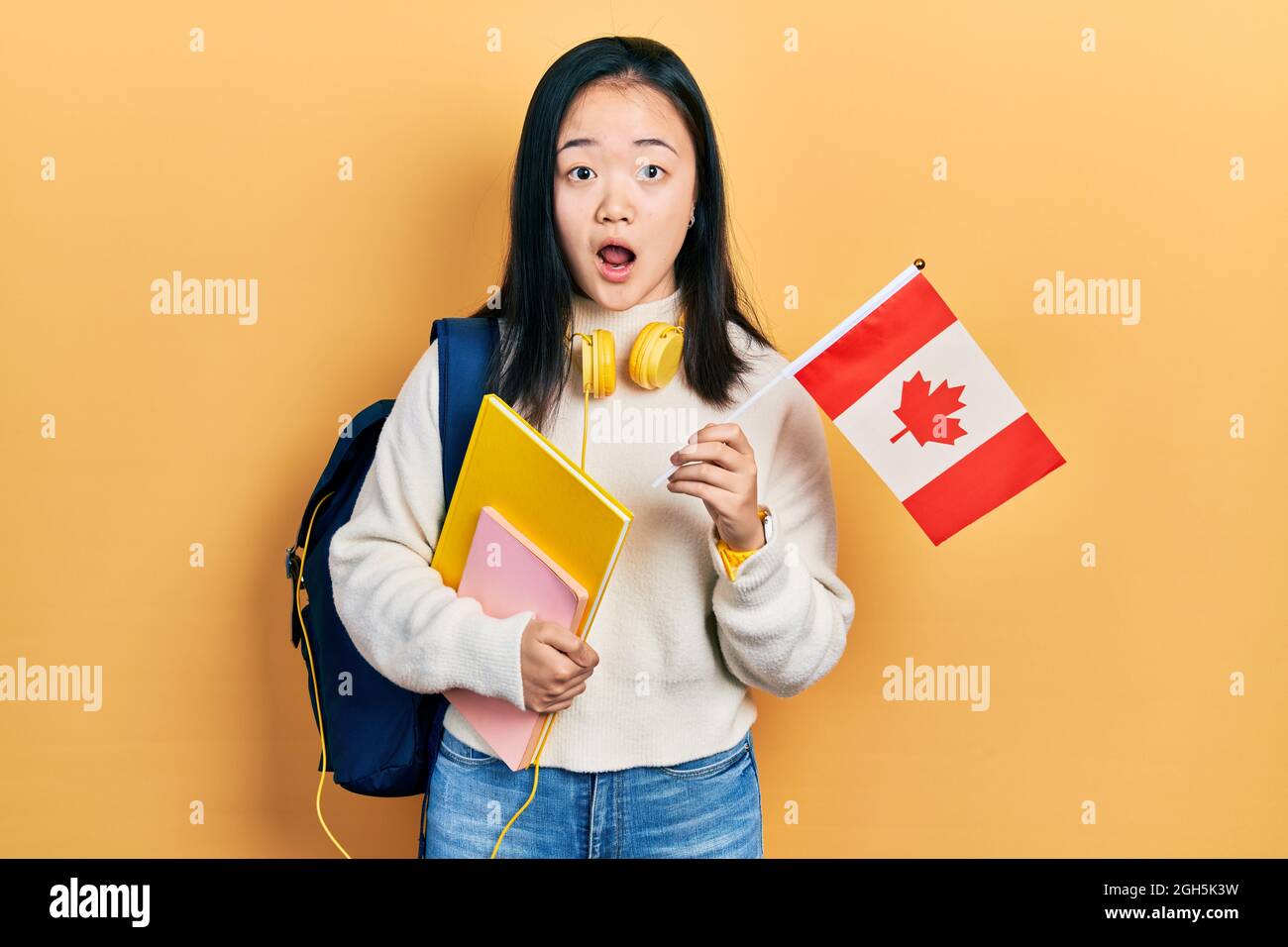 Young chinese girl exchange student holding canada flag afraid and ...