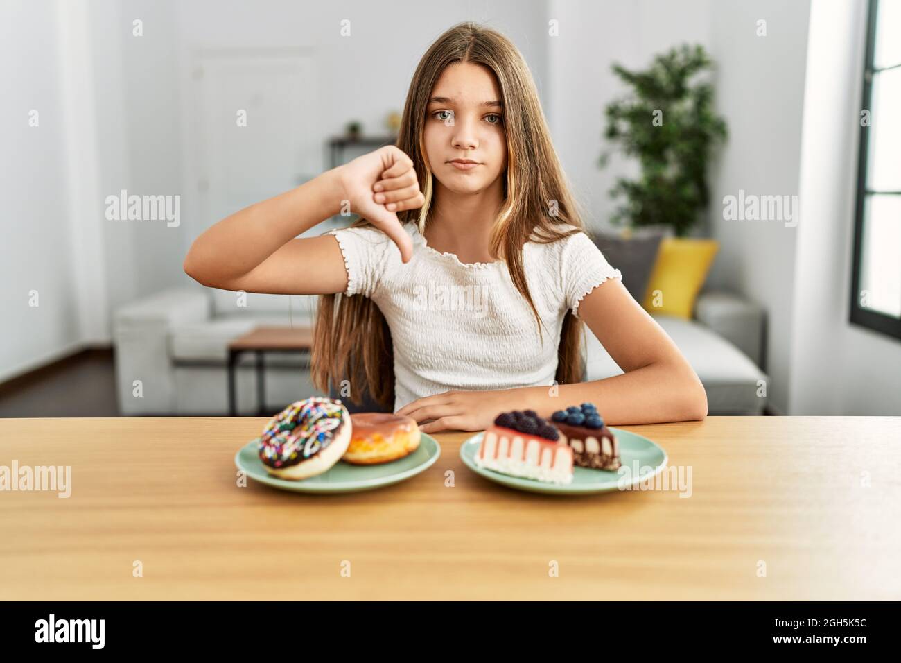 Young brunette teenager eating cakes and sweets with angry face ...