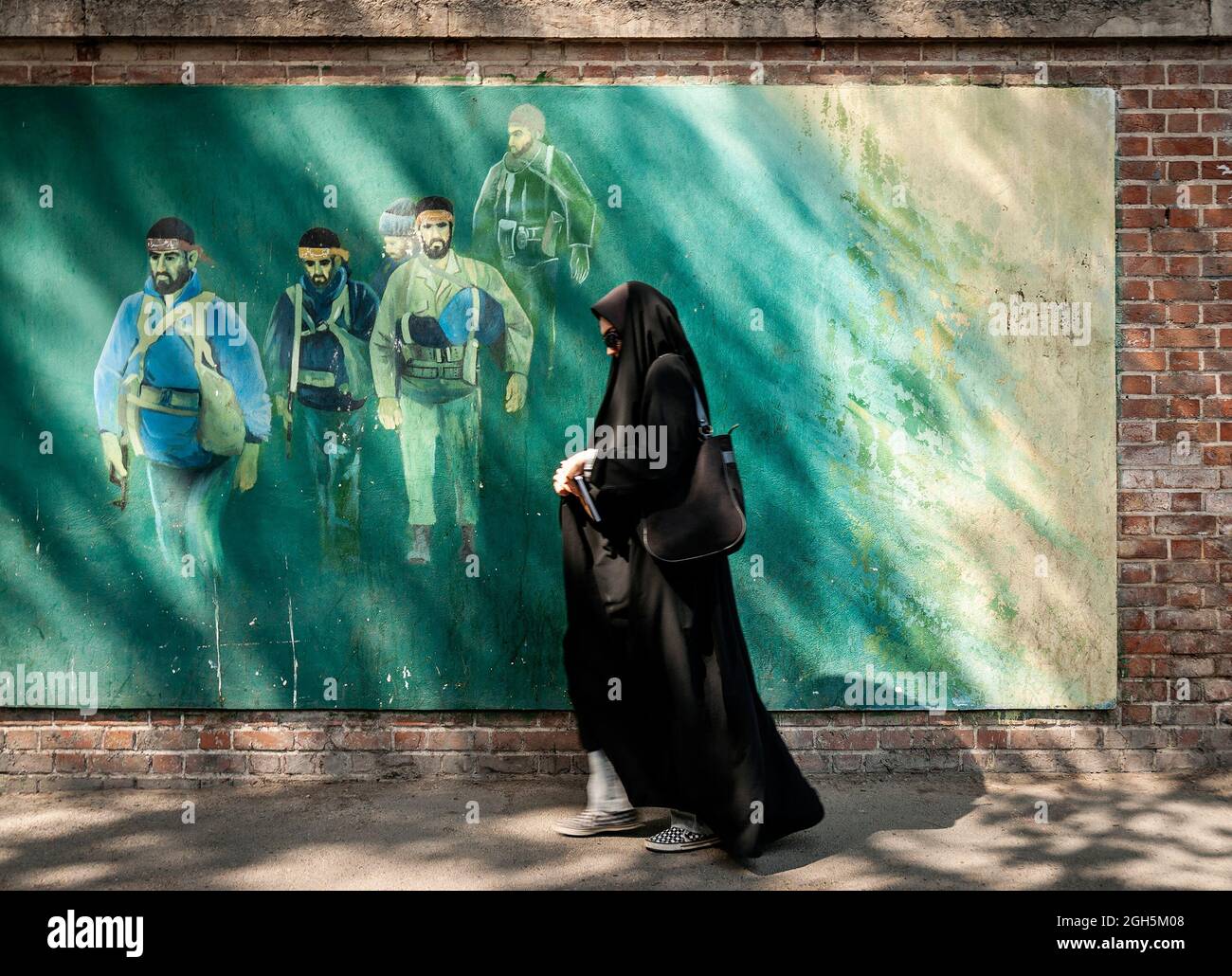 veiled muslim woman walking by revolutionary fighters mural in downtown ...