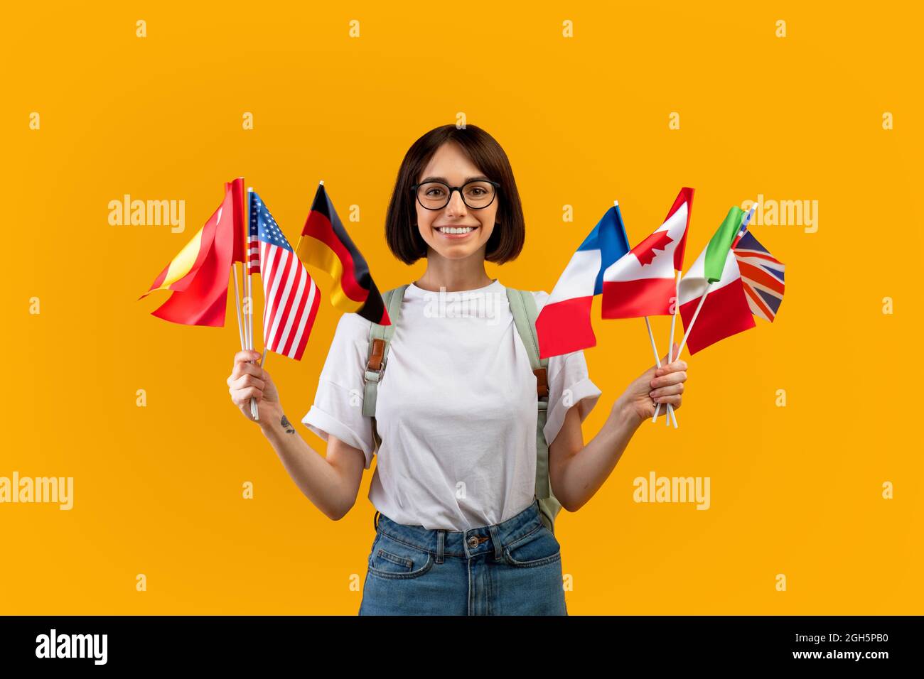 Happy lady showing bunch of diverse flags cheerfully smiling at camera ...