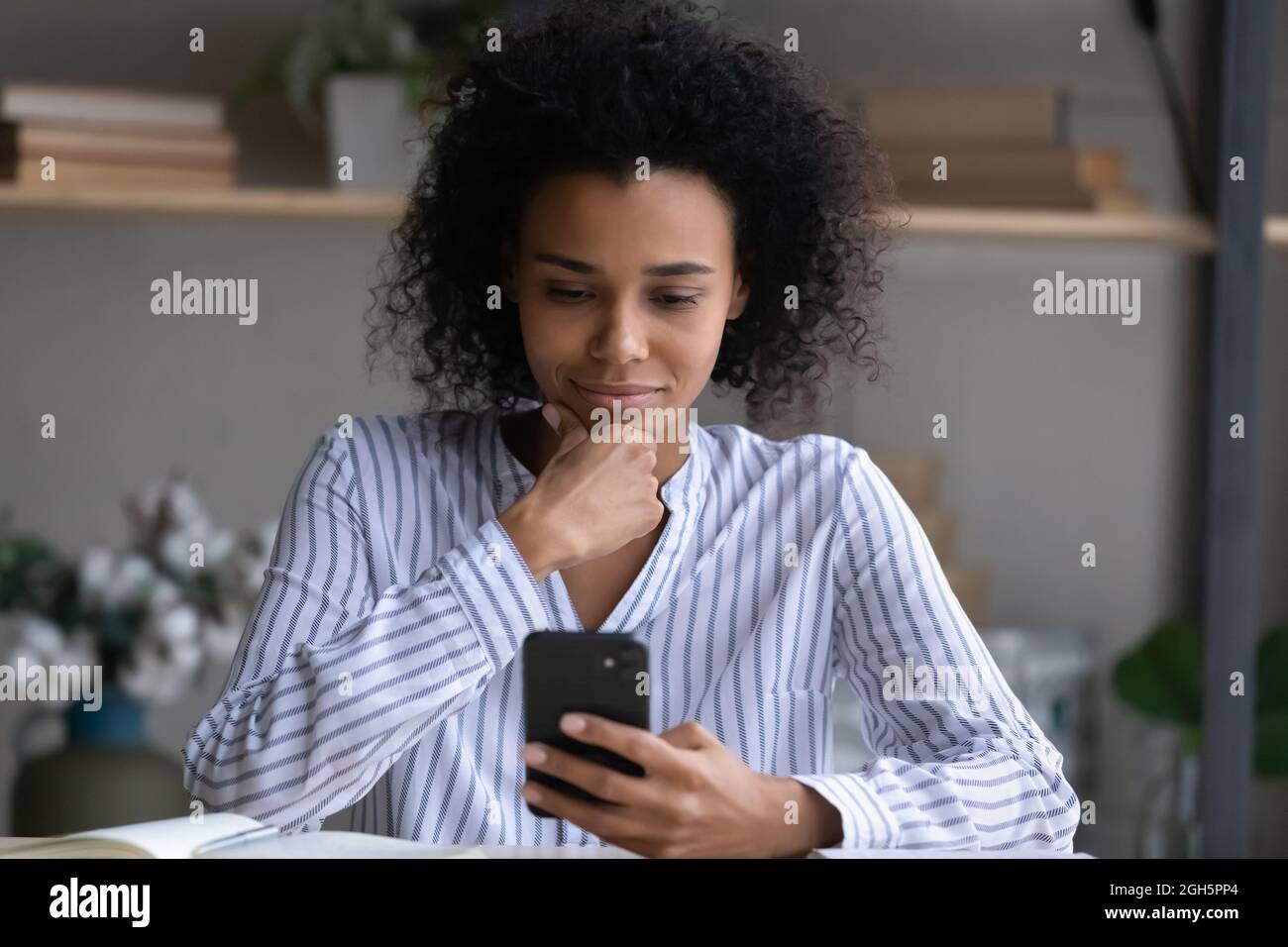 Young mixed race lady think on information on phone screen Stock Photo ...
