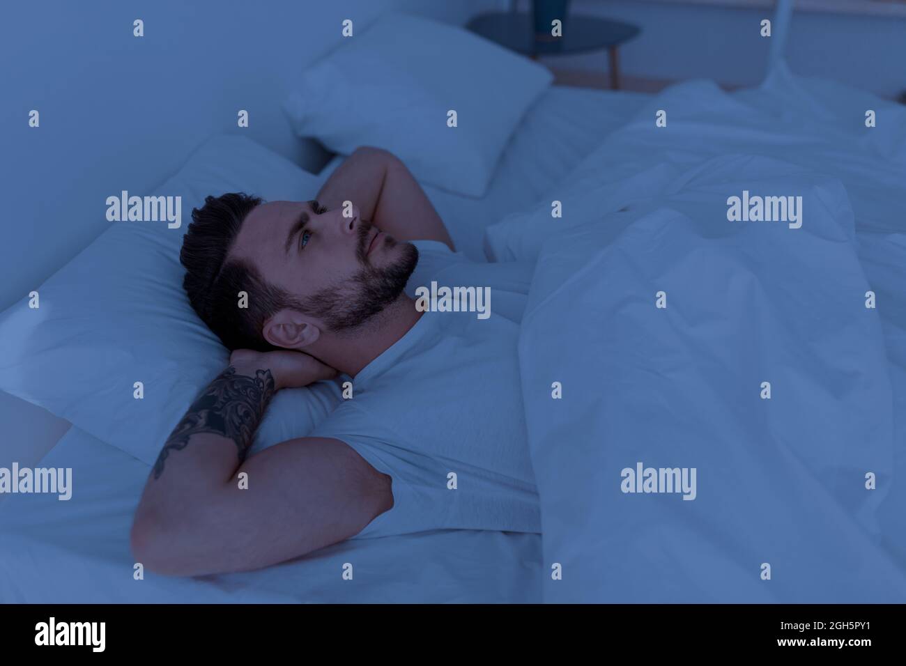 Sleep problems, insomnia and bad thoughts. Young thoughtful man lying ...