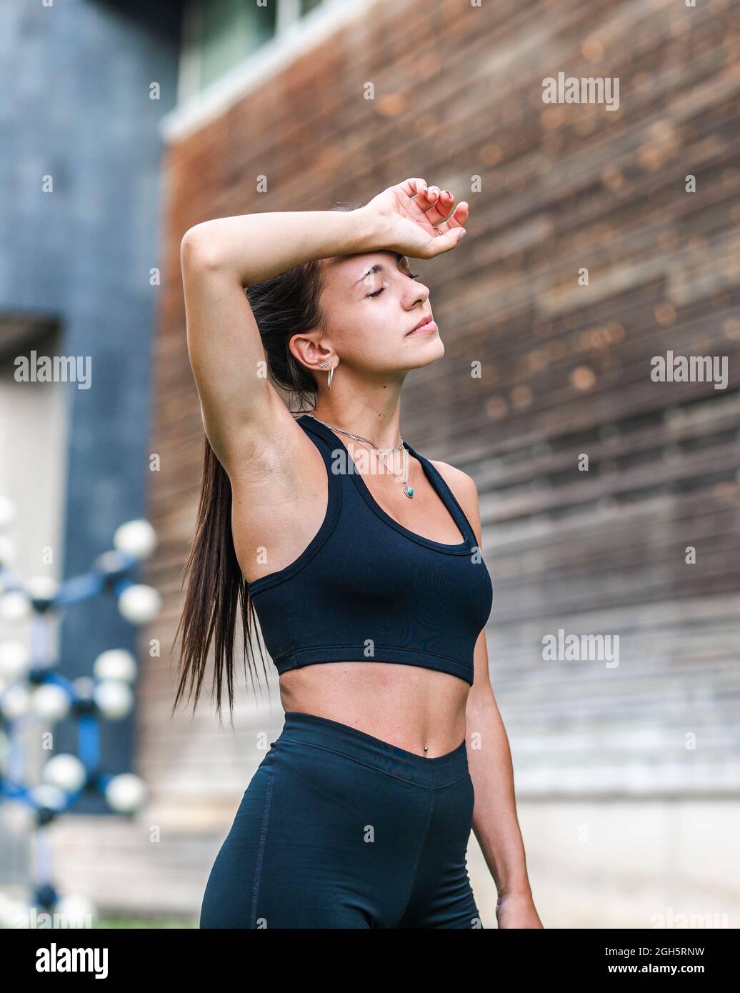 Exhausted female athlete in activewear wiping sweat from forehead with ...