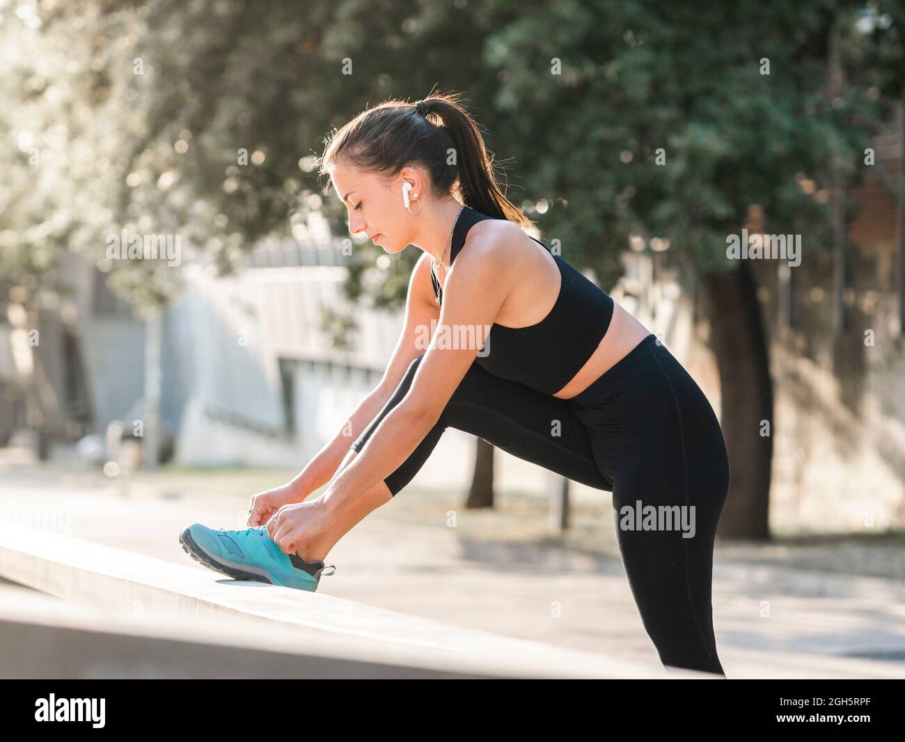 Side view of female athlete tying shoelaces on sneakers and looking ...