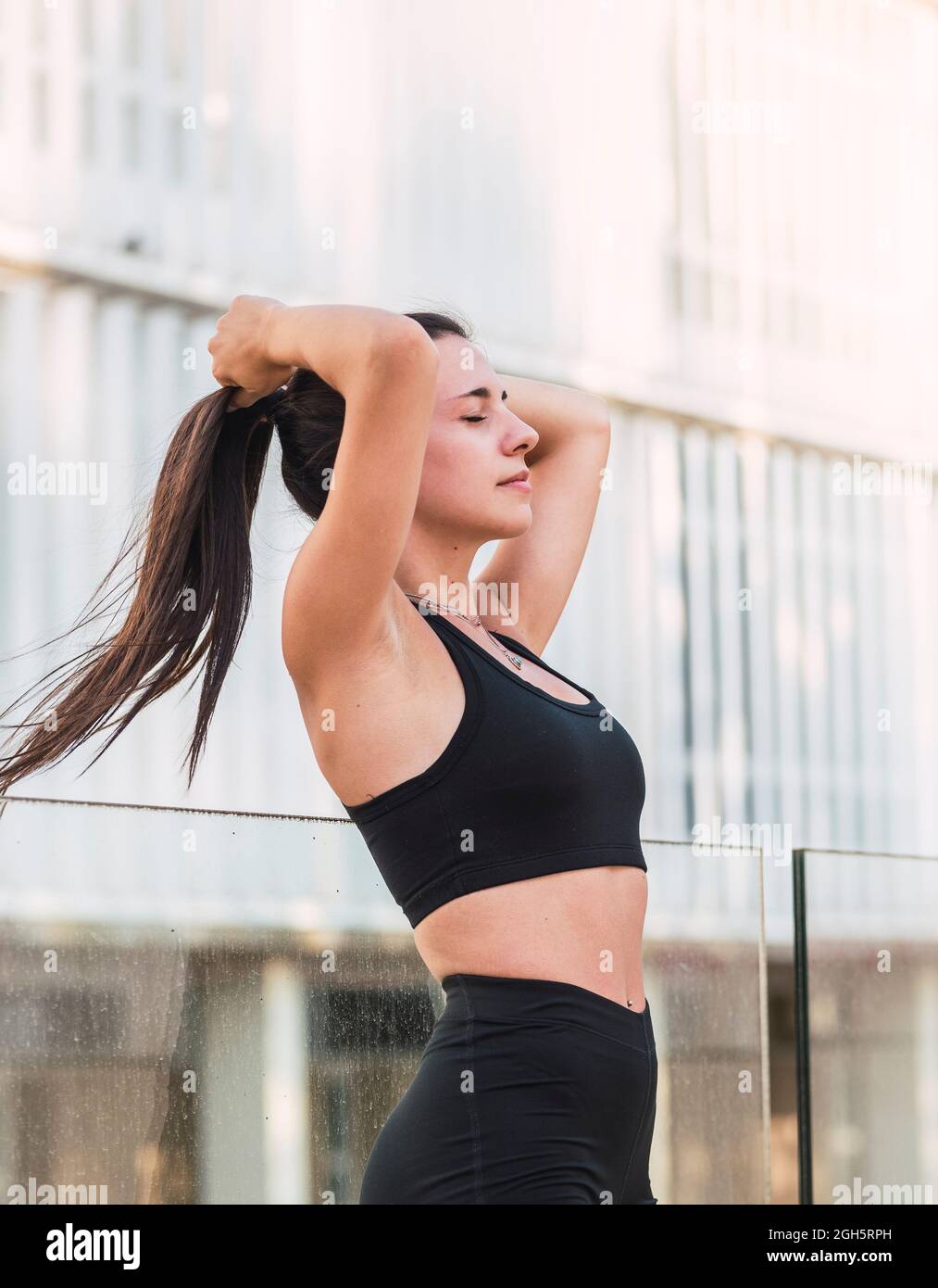 Young sportsWoman with closed eyes doing ponytail during fitness ...