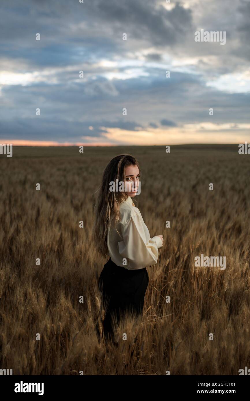 Side view of young mindful female in formal wear with tie looking at ...