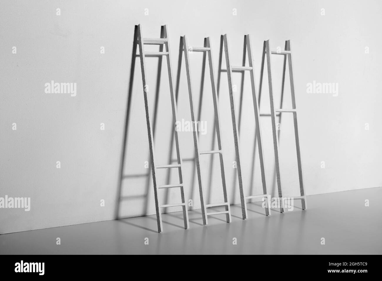 Black and white of ladders against smooth wall with shadow in light ...