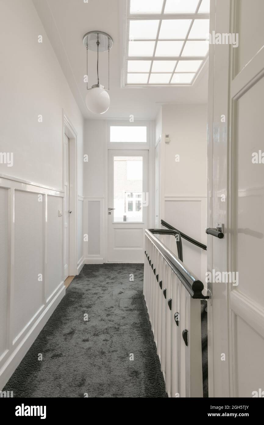 Perspective view of narrow hallway with staircase railing and white ...