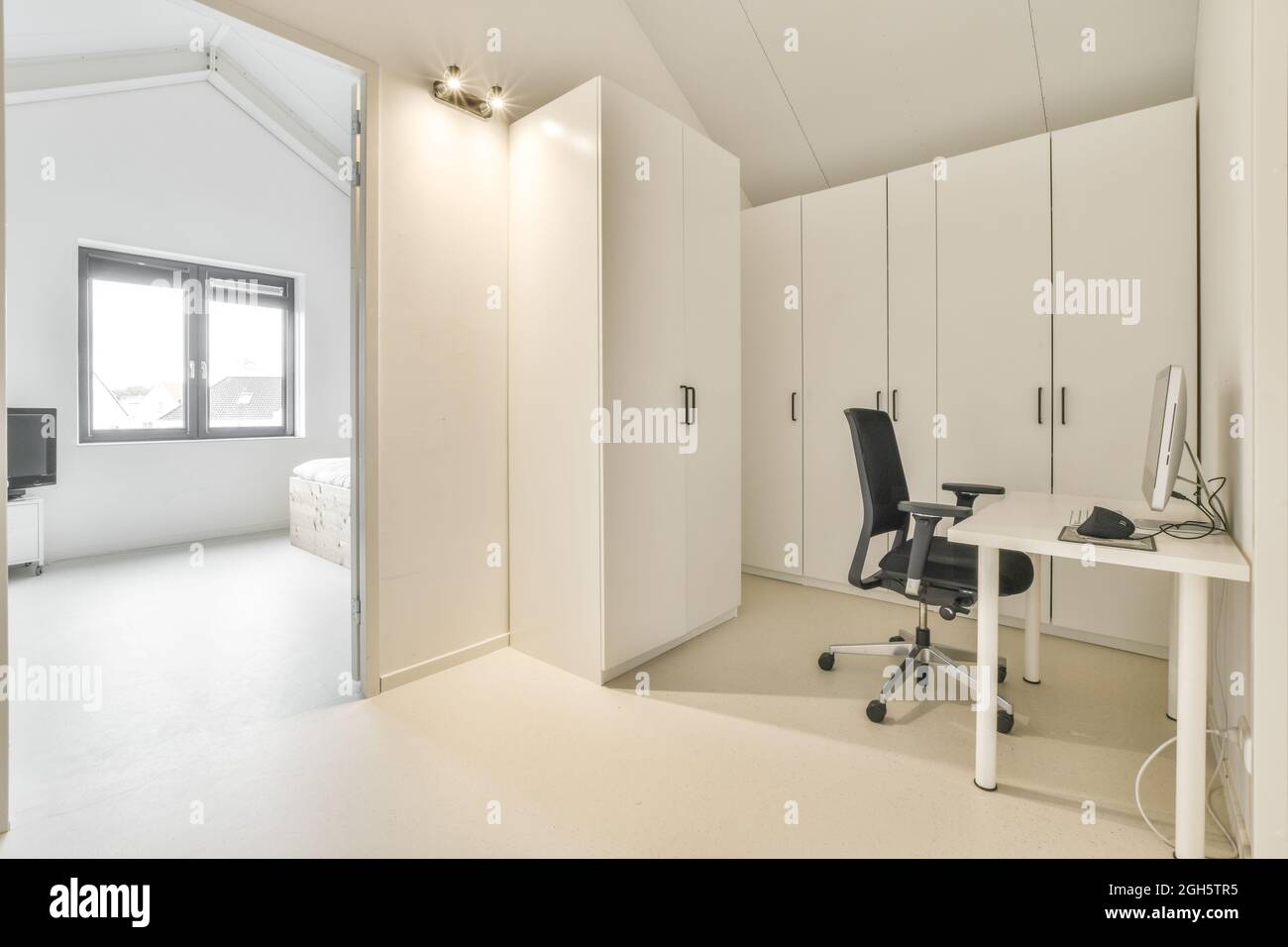 Comfortable chair and table with computer placed near wardrobe in ...