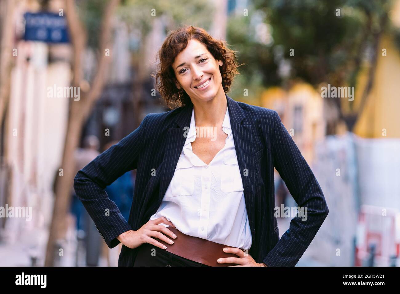 Positive female in classy clothes walking on the street smiling looking ...