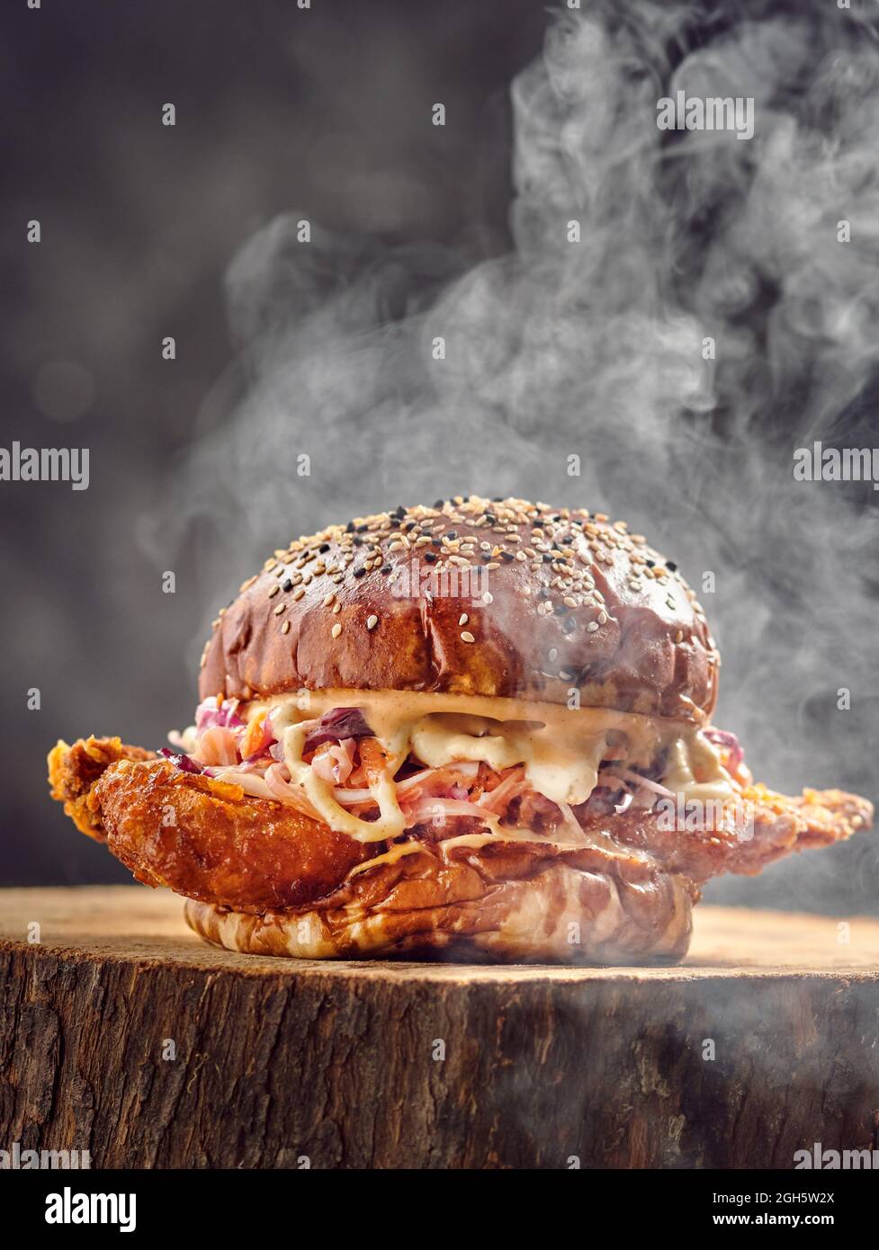 A vertical closeup of a chicken burger on the stump with dark blurred ...
