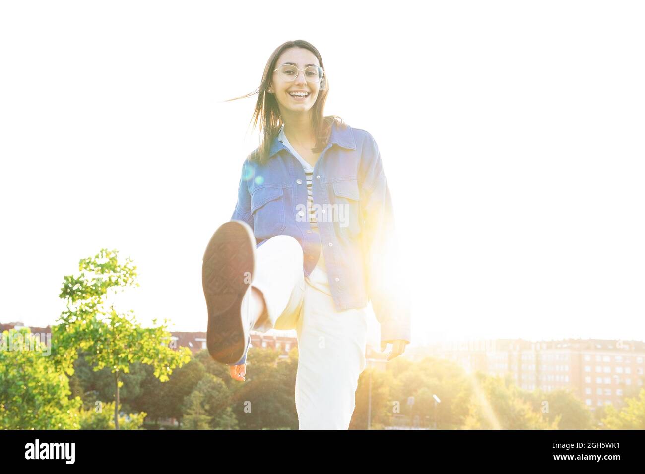 Low angle of stylish positive female kicking leg towards camera on ...