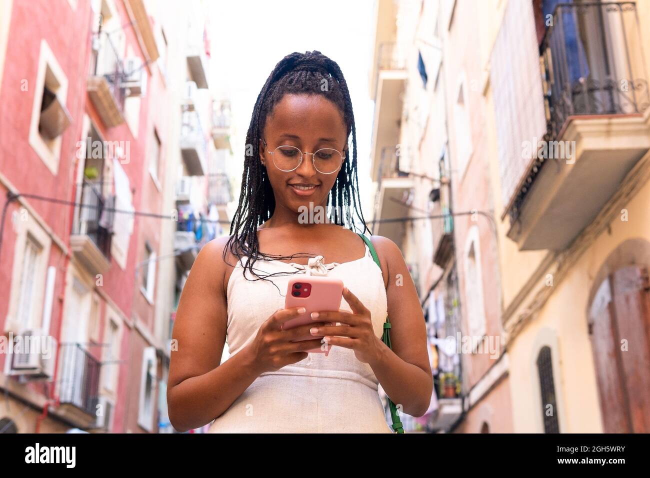 Low angle of smiling African American female with brads messaging on ...