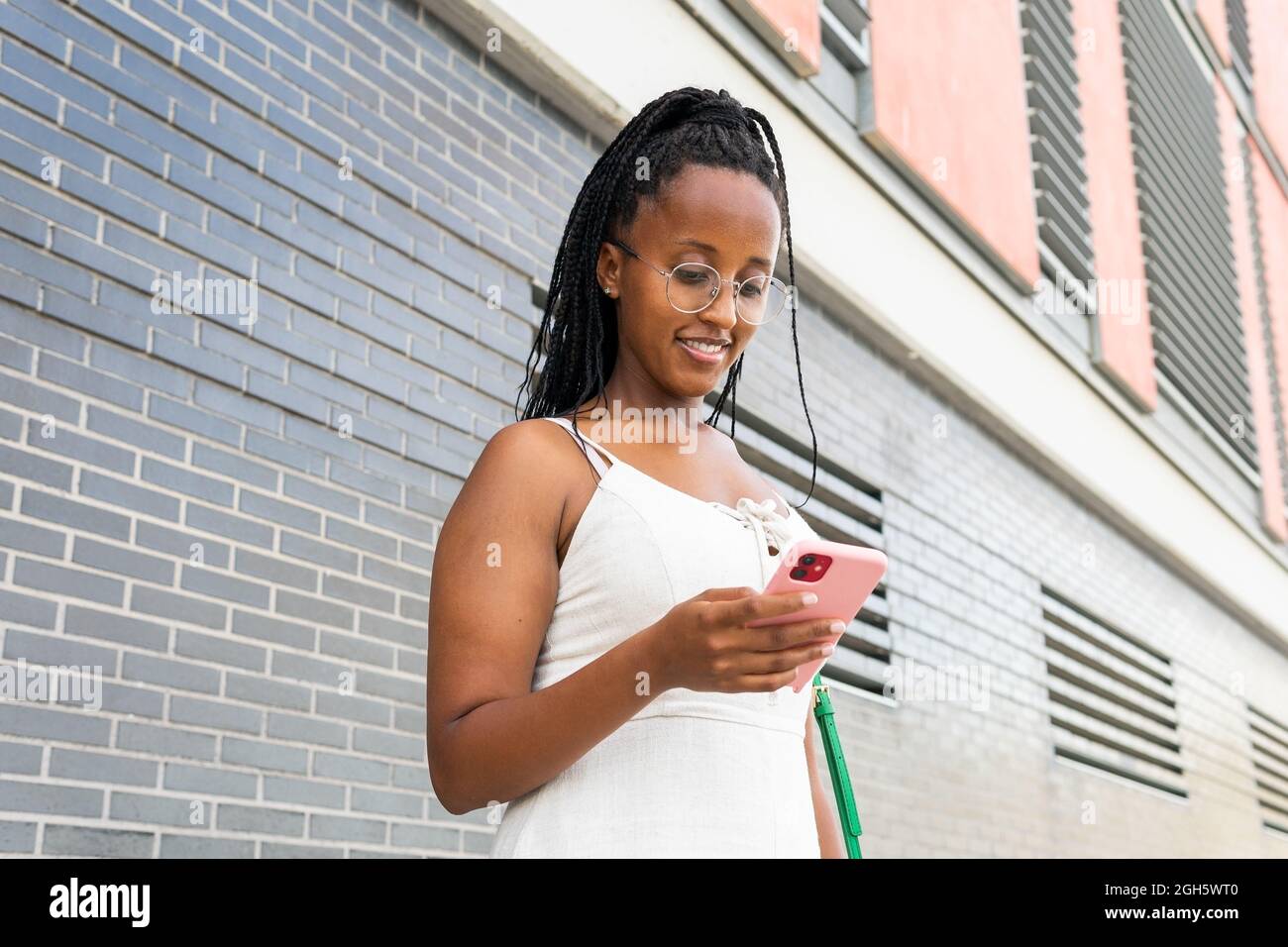 Low angle of smiling African American female with brads messaging on ...