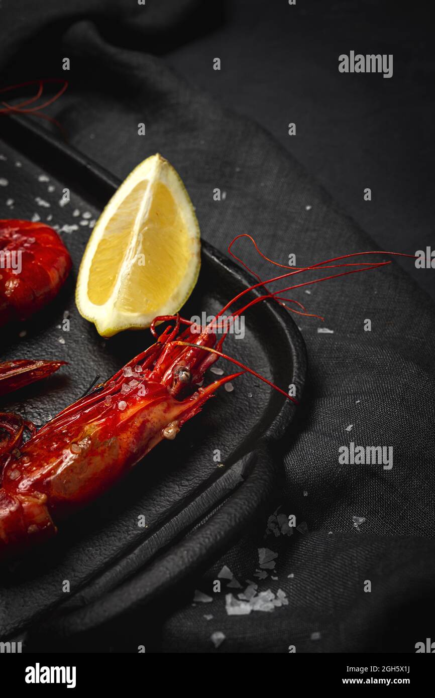 Delicious cooked red prawns on tray with coarse salt and juicy lemon ...