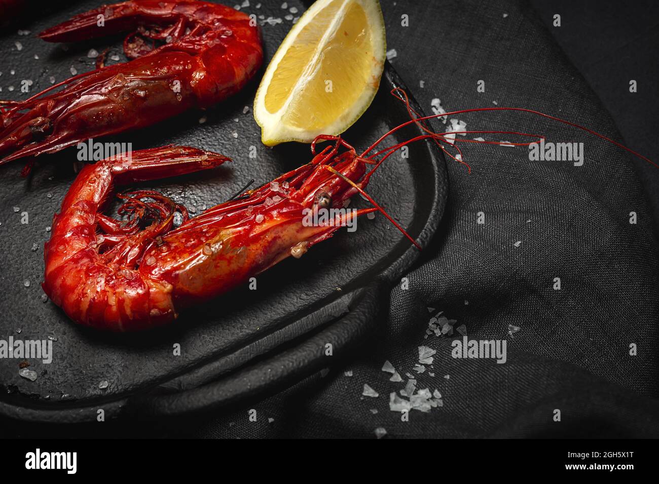 Delicious cooked red prawns on tray with coarse salt and juicy lemon ...