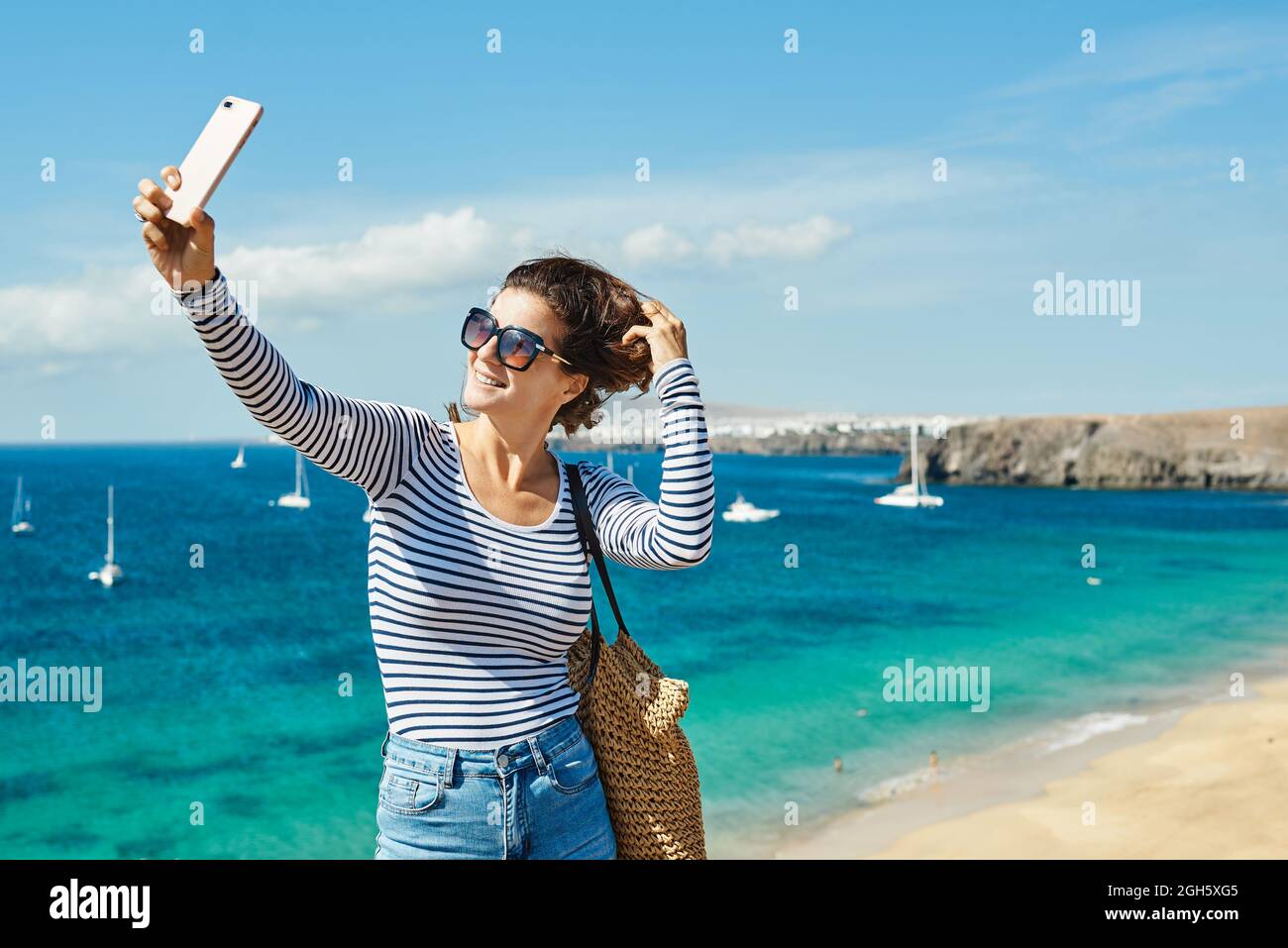 Happy young Woman smiling and touching short hair while taking selfie ...