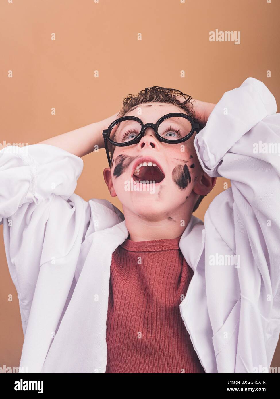Chemist boy in laboratory robe and plastic glasses looking away on ...